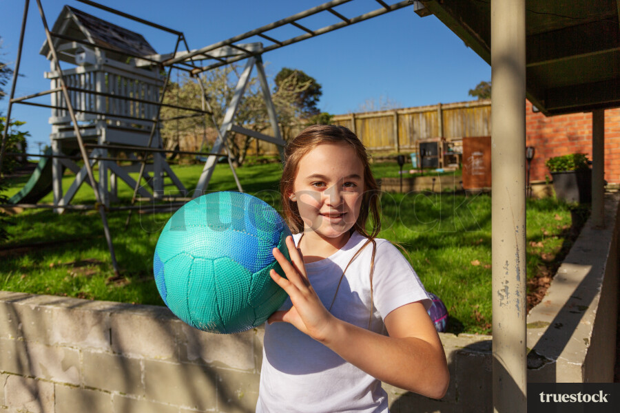 Young Girl Holding Netball in Backyard by Salena Stinchcombe - Truestock