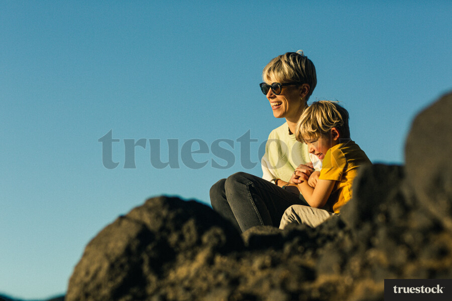 Mother and Son Sitting on Rock by David Marano - Truestock