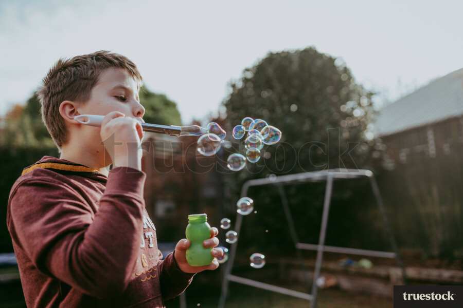 Blowing bubbles in the garden by Liz Robson - Truestock