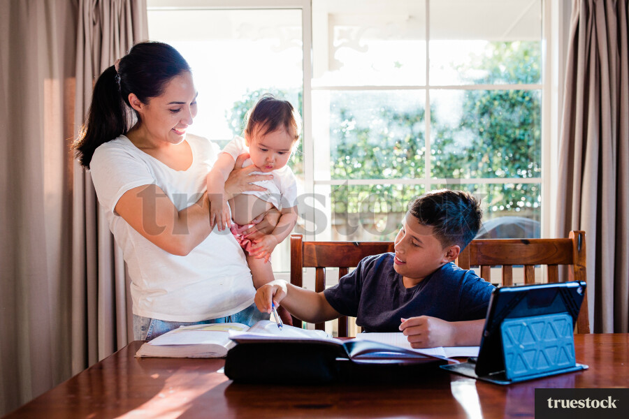 Boy doing homework at dining table by Erica Sinclair - Truestock