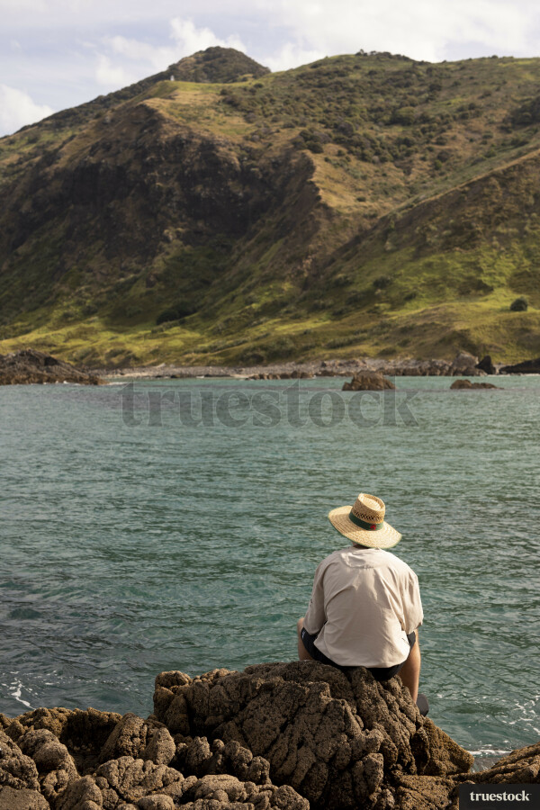Man sitting on rocks by Alex McVinnie - Truestock